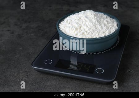 Electronic scales with flour on black table Stock Photo - Alamy