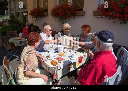 People sit at an outdoor table of a cafe on a hot summer day in Moscow ...