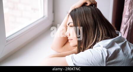 Lady lay down on the windowsill and looks out the window Stock Photo ...