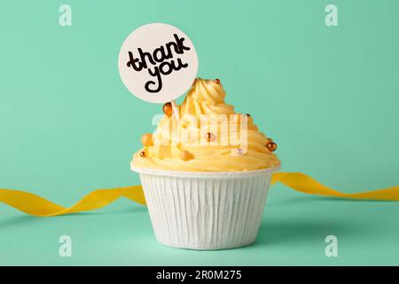 Tasty cupcake and note with phrase Thank You on yellow background ...