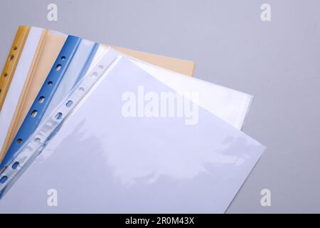 File folders with punched pockets and paper sheets on light grey ...