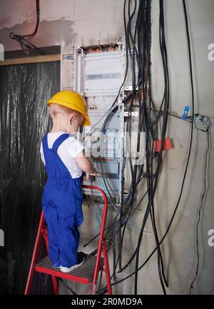 Back view of child construction worker drilling wall with toy electric ...
