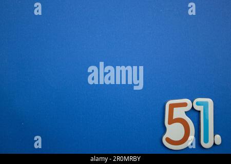 The number 51, placed on a blue background, photographed from above ...