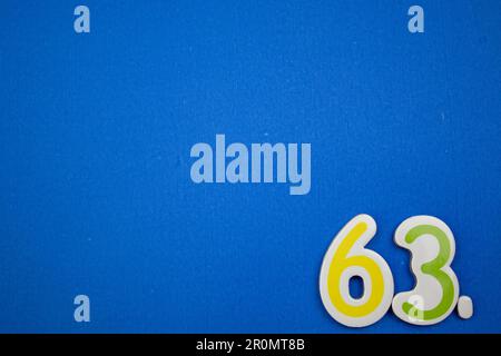 The number 63, placed on a blue background, photographed from above, colored yellow and green ...