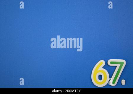 The number 67, placed on a blue background, photographed from above ...