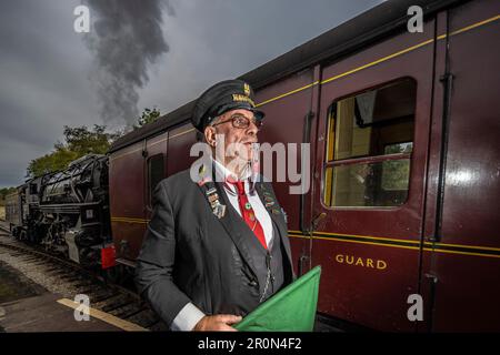 Train guard signalling the departure of historic train on the Keighley ...