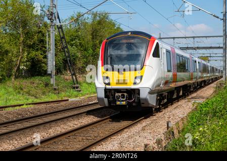 British Rail Class 720 Aventra of Greater Anglia passing at speed through countryside near ...