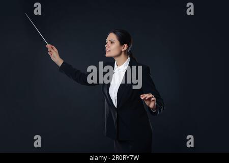 Professional conductor with baton on dark background, back view Stock ...