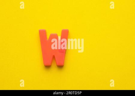 Peach colored plastic letter A uppercase on yellow foamy background ...
