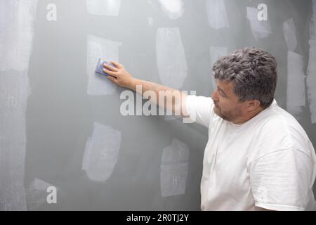 Contractor sanding wall after putty has been applied during repair improvement renovation of an apartment Stock Photo Alamy