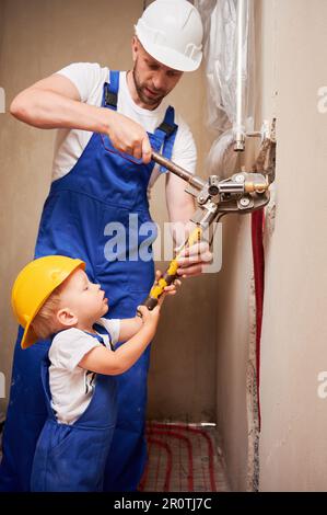 Male worker using pipe pressing tool. Man plumber in work overalls ...
