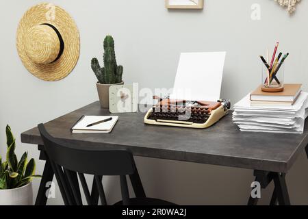 Typewriter and stack of papers on dark table in room. Writer's ...