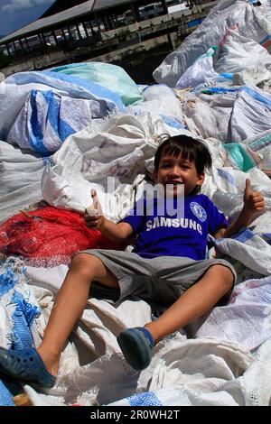 Children playing in piles of trash sacks, looking space in the hot sun ...