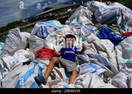 Children playing in piles of trash sacks, looking space in the hot sun ...