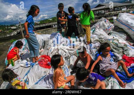 Children playing in piles of trash sacks, looking space in the hot sun ...