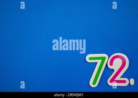 The number 72, placed on a blue background, photographed from above ...