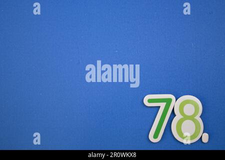 The number 78 in green color, photographed from above, placed on a blue ...