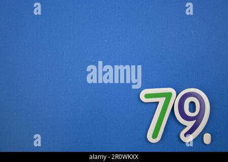 The number 79, placed on a blue background, photographed from above ...