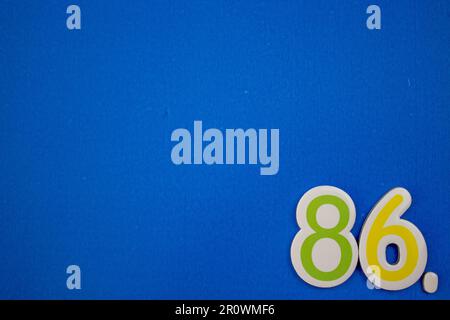 The number 86, placed on a blue background, photographed from above ...
