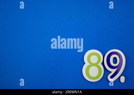 The number 89, placed on a blue background, photographed from above, in ...