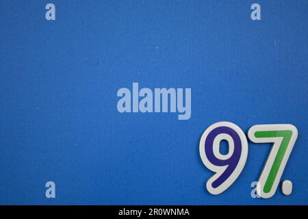 The number 97, placed on a blue background, photographed from above ...