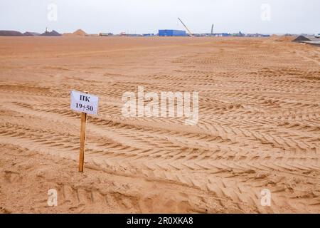 Flat sand subgrade, sign and truck trails. Blue sky on horizon Stock ...