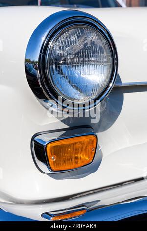 Close-up of the round headlamps and orange turn signal of a white ...