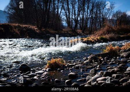 Rolling cobble stones on a blue flowing creek river landscape Stock ...
