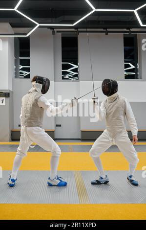 Fencing partners fighting with rapiers practicing attack and defense ...