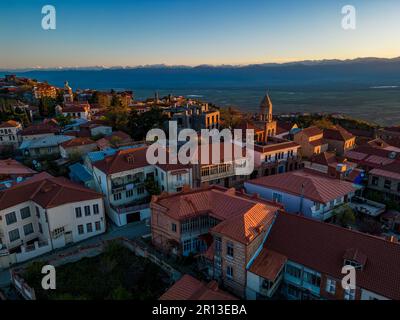 An aerial view of Signagi with vibrant red rooftops and lush greenery ...