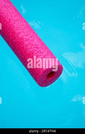 pink pool noodle floating on the blue water Stock Photo - Alamy