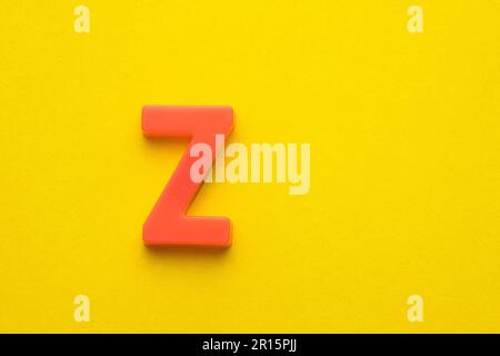 Peach colored plastic letter A uppercase on yellow foamy background ...