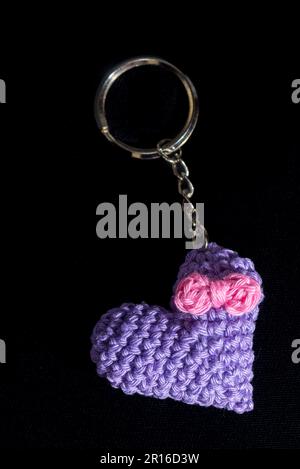 crocheted purple heart-shaped keyrings on a black background Stock ...