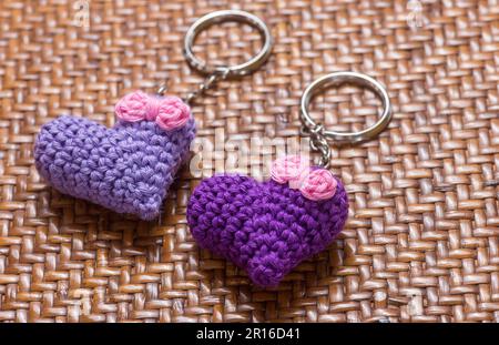A pair of crocheted purple heart-shaped keyrings on a white background ...