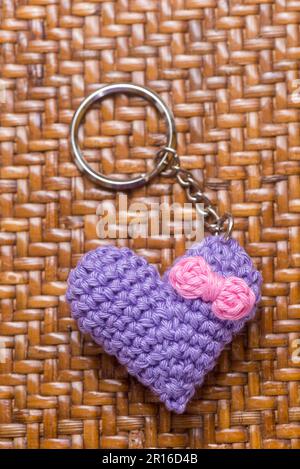 A single crocheted purple heart-shaped keyring on a textured background ...