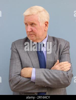 Senior man in suit faced by multiple microphones with hands holding and ...