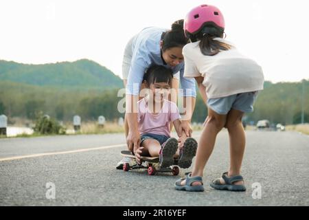 Children riding skateboard in summer park. Little girl and boy learn to ...