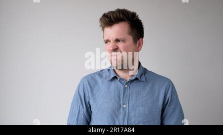 European young man is hesitating and unwilling to make decisions. He is ...