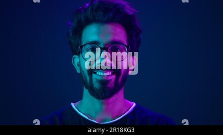 Happy Indian man in ultraviolet neon studio background champion coding ...