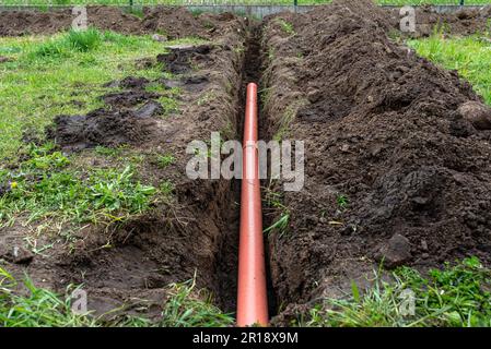Orange PVC pipe buried in the ground connected to the gutter, used to ...