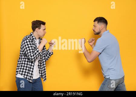 Two emotional men fighting on beige background Stock Photo - Alamy