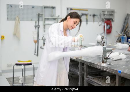 Technician sculpting plaster cast for socket at prosthetic factory ...