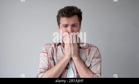 The tired European young man, lacking energy, closes his face with ...