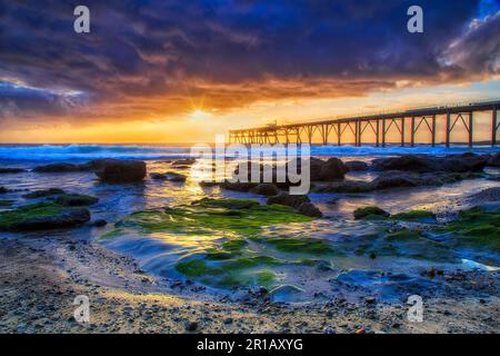 Colourful seascape sunrise at historic timber jetty of Middle Camp ...