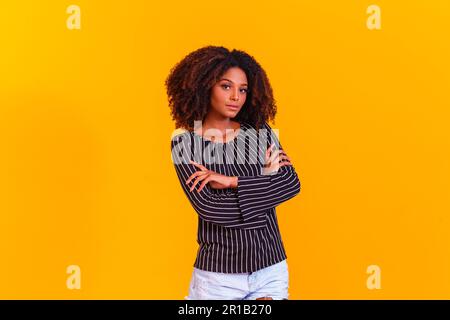 afro woman cross arms in yellow background Stock Photo - Alamy