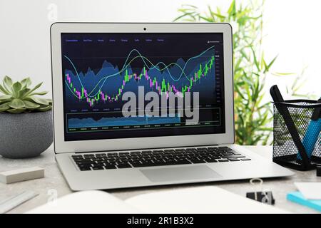 Modern laptop, houseplants on table and sticky notes on white wall ...