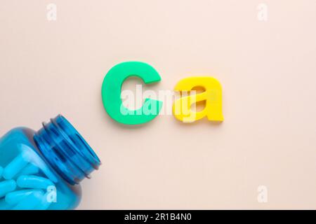 Calcium symbol made of colorful letters and white pills on light blue ...