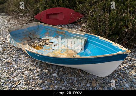 An abandoned broken boat full of holes lying on the seashore in the off ...