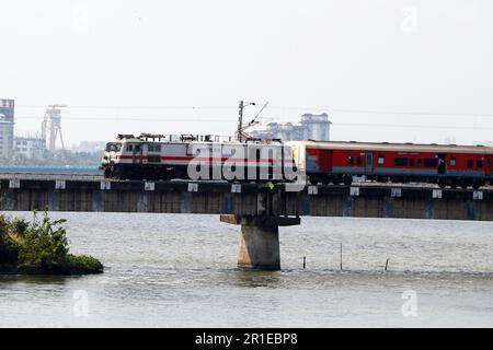 indian railway train moving very quickly on a bridge over the river in ...