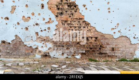 The wall of a building battered by rocket fragments in a war zone ...